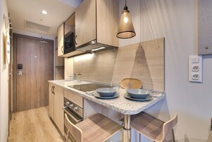 Cozinha moderna com armários de madeira, pia de aço inoxidável e luminária pendente.