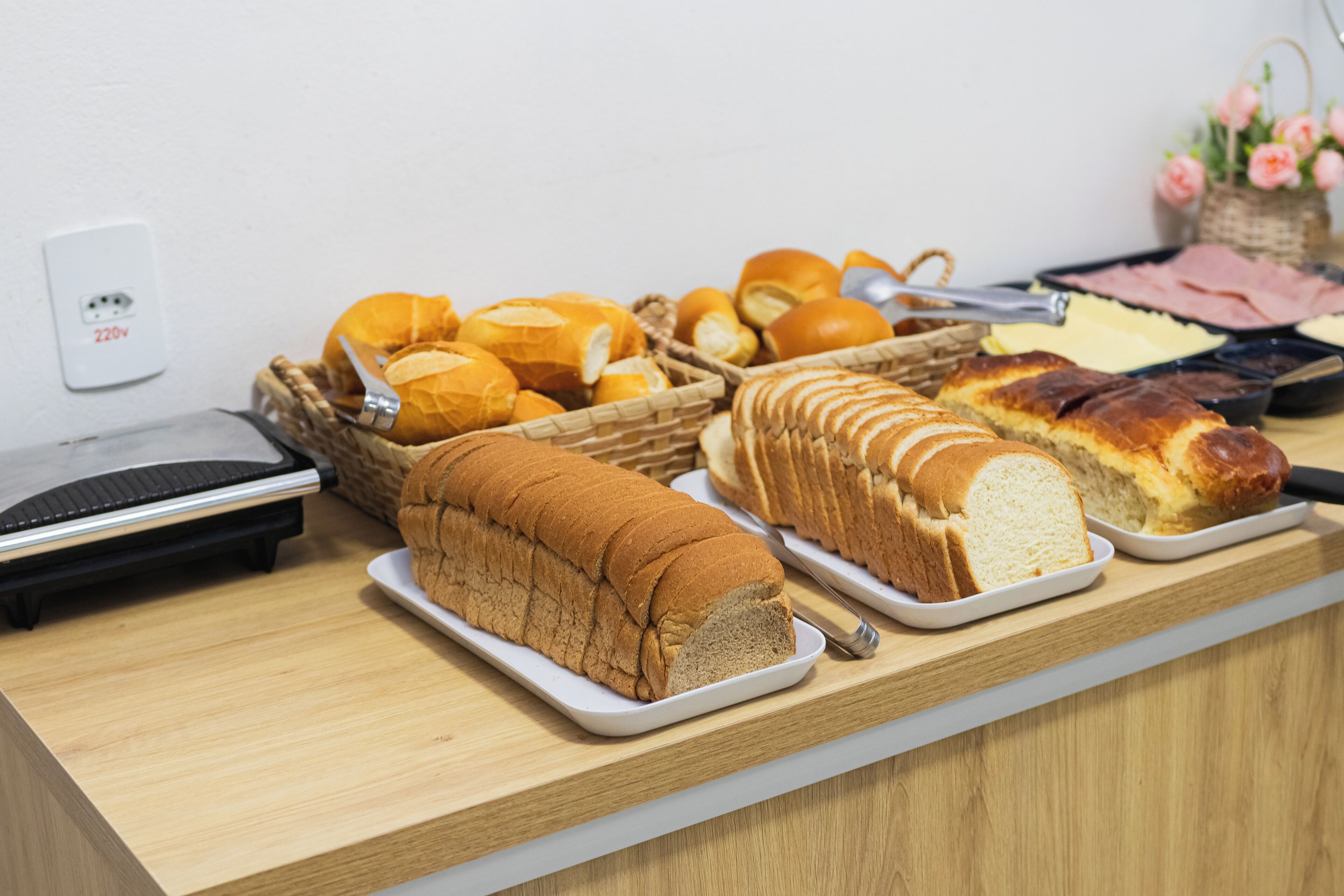 Uma mesa de buffet com diversos pães e doces.