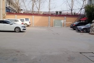 Um estacionamento com vários carros, um edifício com telhado vermelho e uma porta.