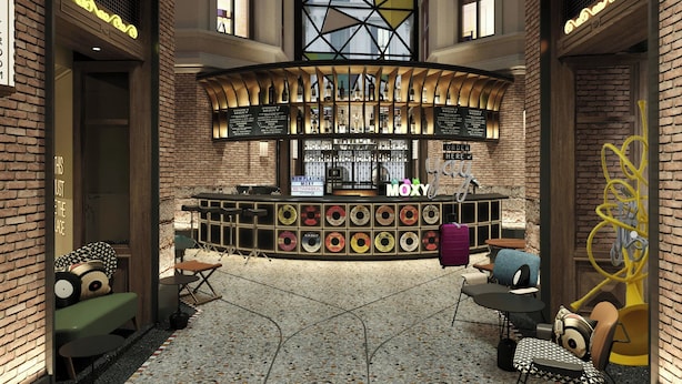 Uma área de bar com balcão central exibindo diversas marcas de bebidas, rodeada por assentos e um design de janela geométrico singular.