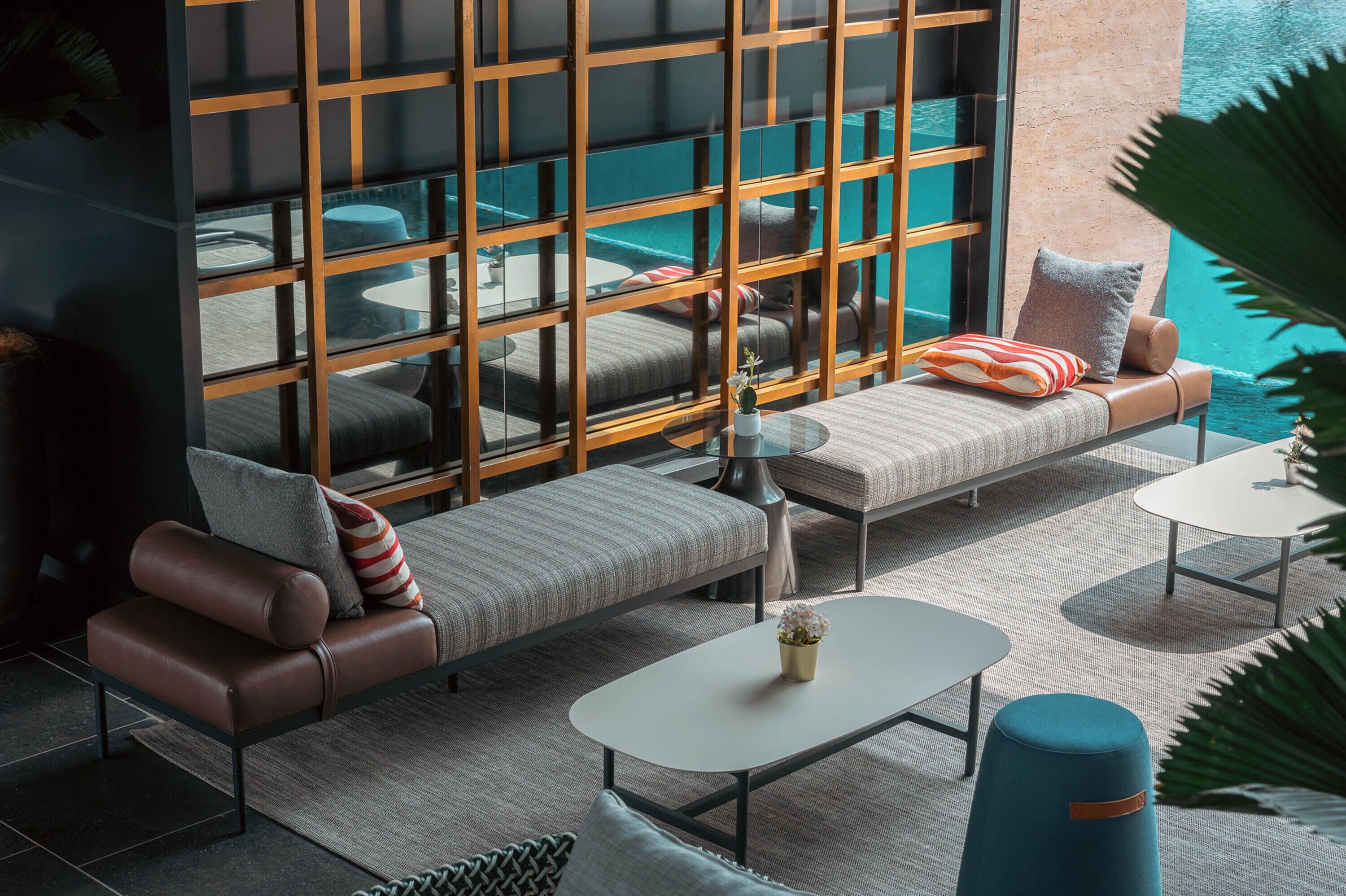 Uma área de estar moderna ao ar livre, com um sofá, poltronas e uma mesa de centro, com vista para uma piscina.