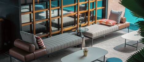 Uma área de estar moderna ao ar livre, com um sofá, poltronas e uma mesa de centro, com vista para uma piscina.