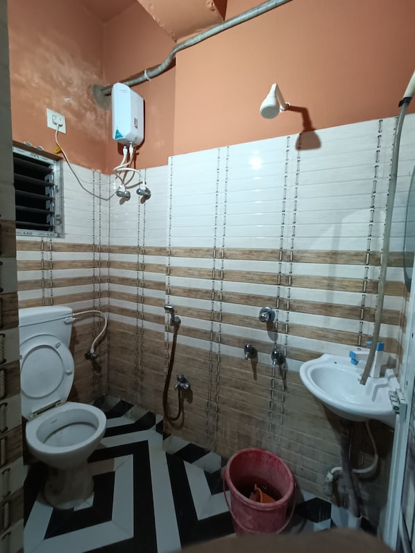 Casa de banho com paredes de azulejos listrados, uma sanita, uma pia e um chuveiro.