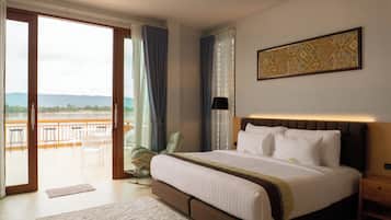 Quarto de hotel com cama, mesa de cabeceira, cadeira, janela com cortinas e vista para o exterior.
