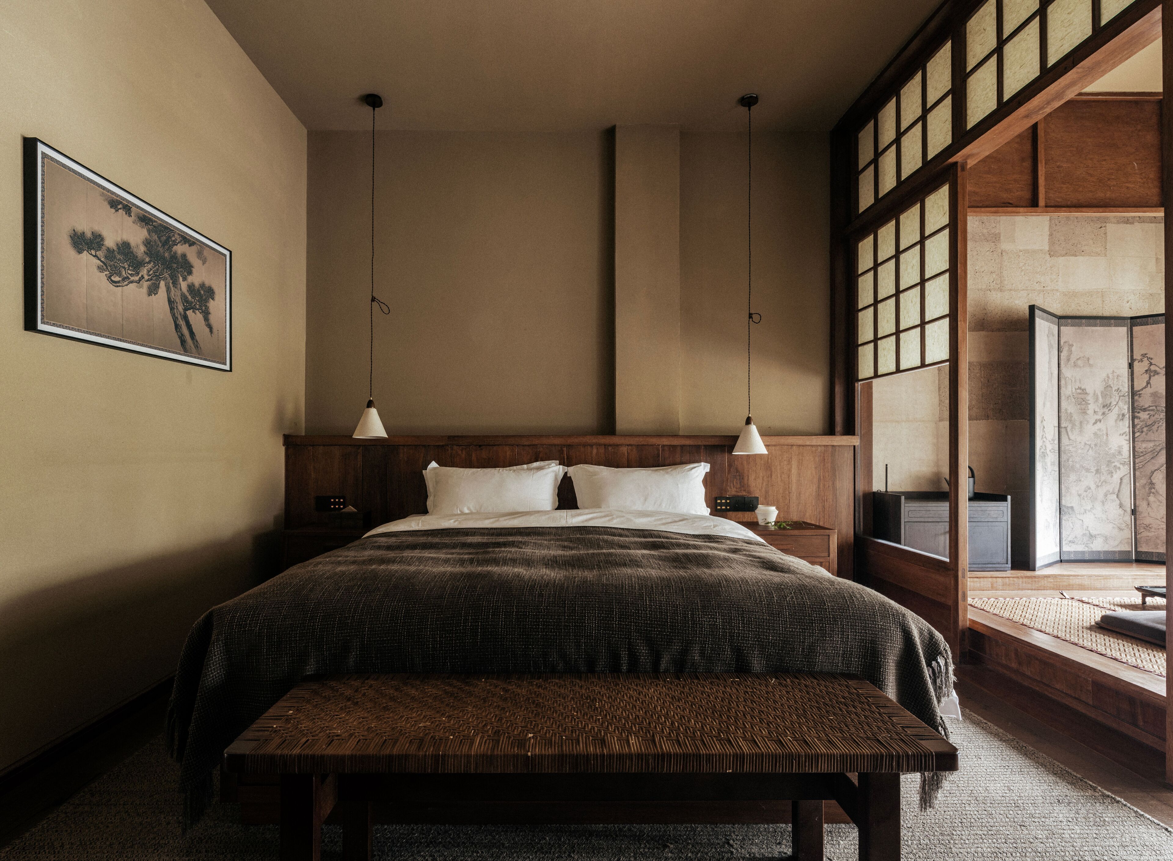 Quarto com cama grande, mesas de cabeceira, abajur e porta deslizante tradicional.