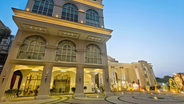 Um hotel imponente com fachada simétrica, amplas janelas em arco e uma entrada central com colunas.