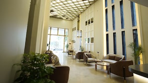 Um hall amplo com pé direito alto, janelas grandes e mobiliário moderno.