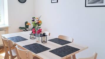 Uma área de refeições com uma mesa e cadeiras de madeira, um vaso com flores e um quadro na parede.