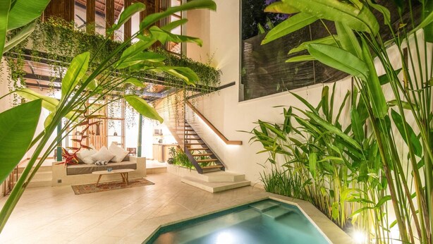 Um espaço interior moderno com piscina, escadaria e vegetação exuberante.