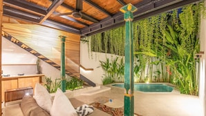 Uma área externa moderna com piscina, piso de madeira e vegetação exuberante.