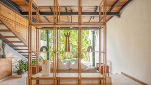 Um interior moderno com um banco de madeira, uma escada e vista para o verde lá fora.