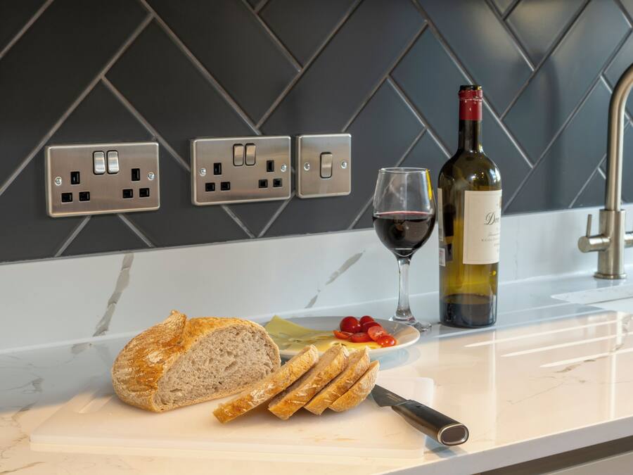 Uma bancada de cozinha com um pão, uma garrafa de vinho e um copo de vinho tinto.