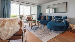 Uma sala de estar moderna com um sofá azul, uma mesa de centro de madeira e uma poltrona aconchegante.