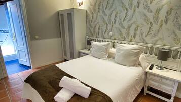Quarto de hotel com cama, mesa de cabeceira, guarda-roupa e ventoinha no teto.