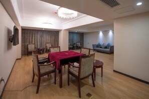Uma sala de jantar com mesa, cadeiras, um sofá e uma televisão na parede.