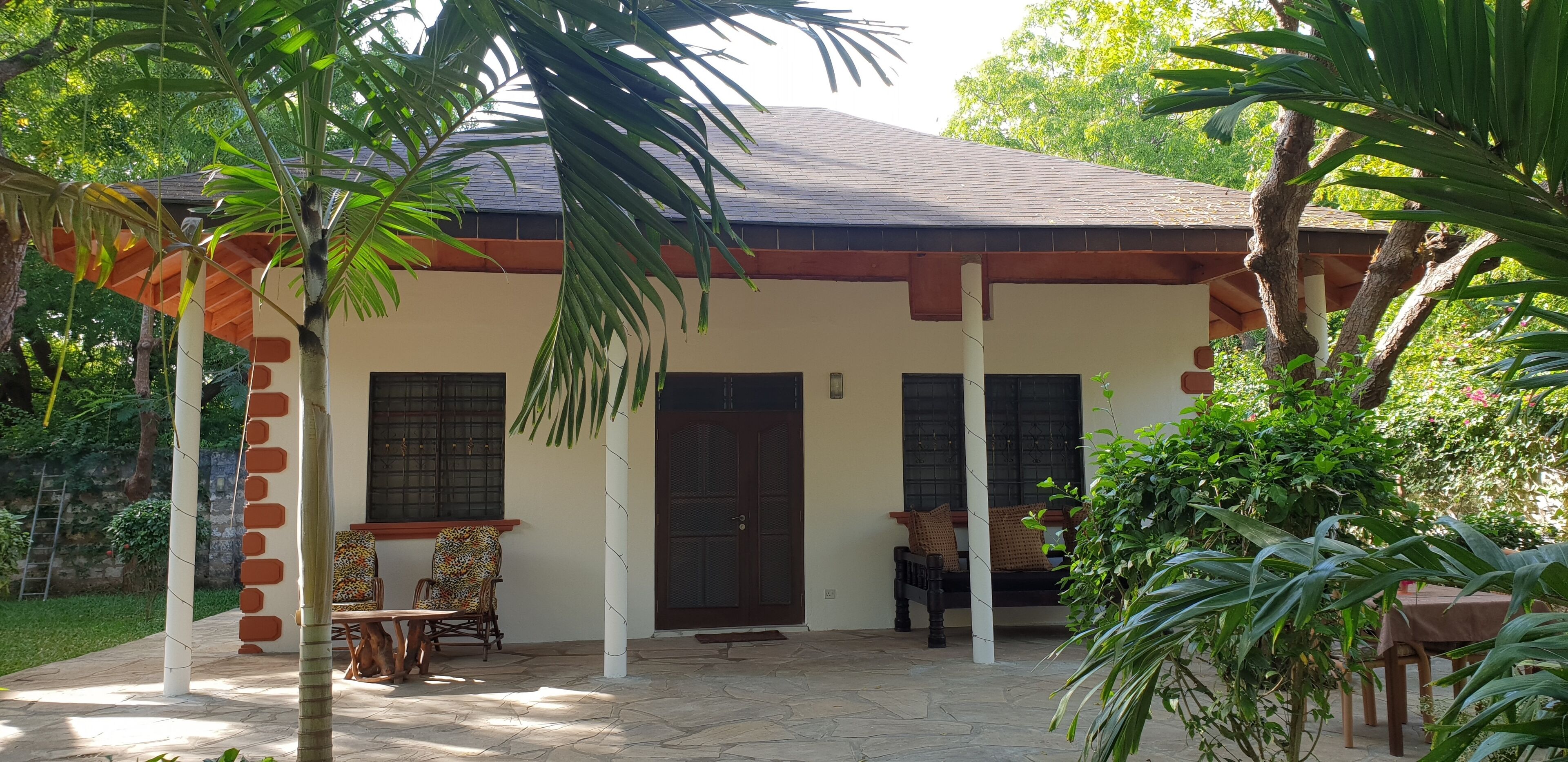 Uma casa com um pátio ladrilhado, uma área de estar coberta e uma porta com janela.