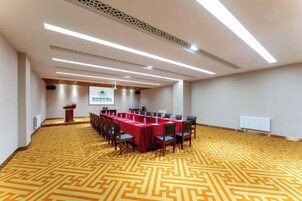 Uma sala de conferências com uma mesa comprida, cadeiras e um púlpito.