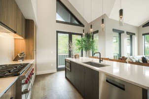 Uma cozinha moderna com uma ilha grande, eletrodomésticos de aço inoxidável e janelas amplas.
