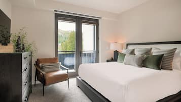 Quarto com uma cama grande, uma cadeira, cômoda e vista pela porta de correr.