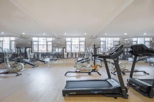 Uma academia com várias esteiras, bicicletas ergométricas e aparelhos de musculação.