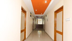 Um corredor com piso de azulejos, portas de madeira e teto com iluminação embutida.