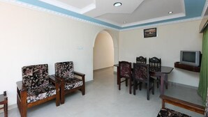 Sala de estar com área de jantar, com móveis de madeira e televisão.
