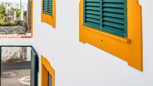 Um edifício com duas janelas, com portaria verde e molduras amarelas.