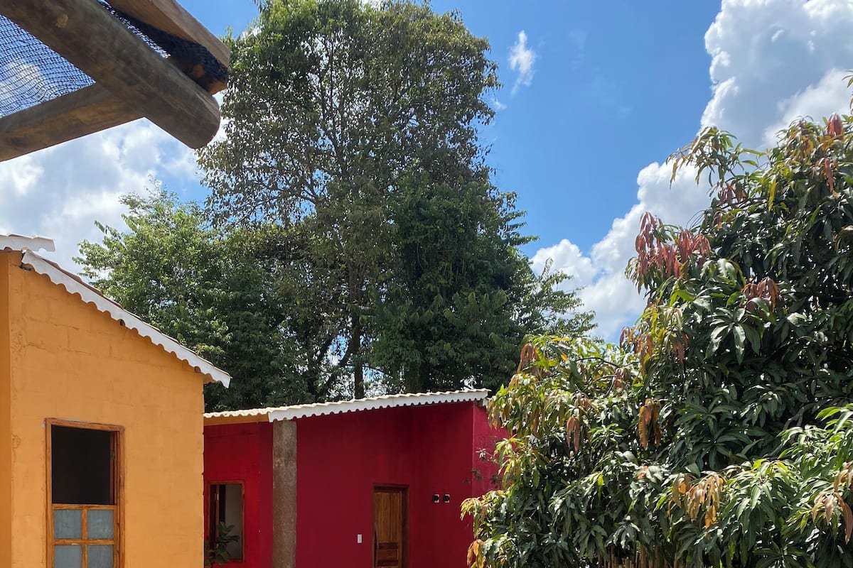 Um pequeno edifício de dois andares com fachada vermelha e amarela, uma porta de madeira e uma janela pequena.