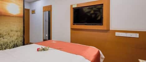 Quarto de hotel com cama, TV fixada na parede e porta que dá para outro cômodo.