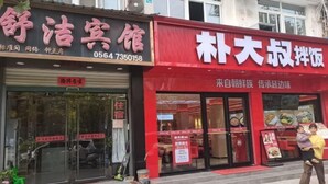 Um hotel com entrada fechada e um restaurante vermelho na rua de enfrente.