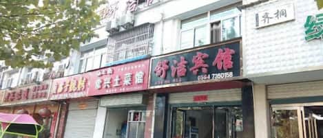 Fileira de lojas com persianas fechadas, uma delas com placa indicando o estabelecimento 'Sheng Qiu An'.