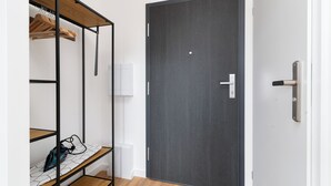 Um quarto com guarda-roupa, um banco com uma mala e uma porta com puxador.