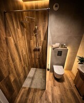 Uma casa de banho moderna com cabine de duche em madeira, sanita e lavatório.