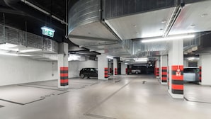 Garagem de estacionamento em vários níveis, com sinalização direcional clara, vagas demarcadas e defensas de segurança.