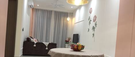 Uma sala de jantar com toalha xadrez, quatro banquetas, um candelabro e uma parede decorada com flores.