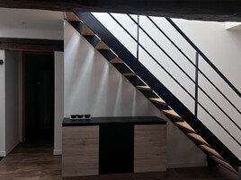 Uma escadaria moderna com design em preto e branco, que leva a um patamar de madeira com bancada preta e duas tigelas pretas.