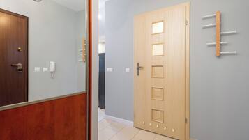 Um corredor com uma porta de madeira, um porta-toalhas na parede e um interruptor de luz.
