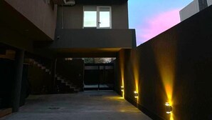 Um edifício moderno com telhado plano, varanda e escadaria que leva à entrada.