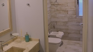 Uma casa de banho com toucador bege, espelho, sanita e banheira.