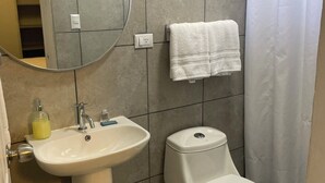 Um banheiro com pia, espelho, vaso sanitário e cortina de chuveiro.