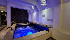 Uma área de spa com hidromassagem, parede de pedra e luminárias fixadas na parede.