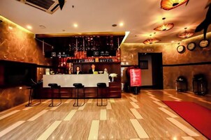 Um saguão de hotel com balcão de recepção, área de bar e assentos.