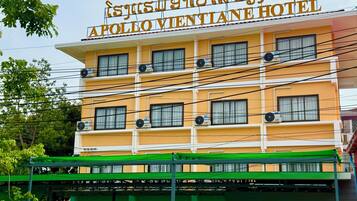 Um hotel de vários andares com fachada amarela e uma placa em idioma estrangeiro.