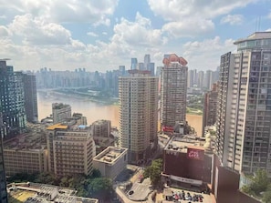 Paisagem urbana com arranha-céus, um rio e uma ponte ao fundo.