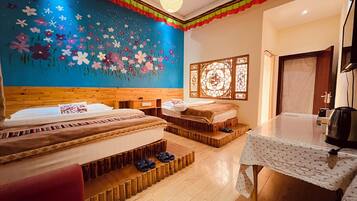 Quarto de hotel com duas camas, piso de madeira, parede decorativa com motivos florais e um divisório de estilo tradicional.
