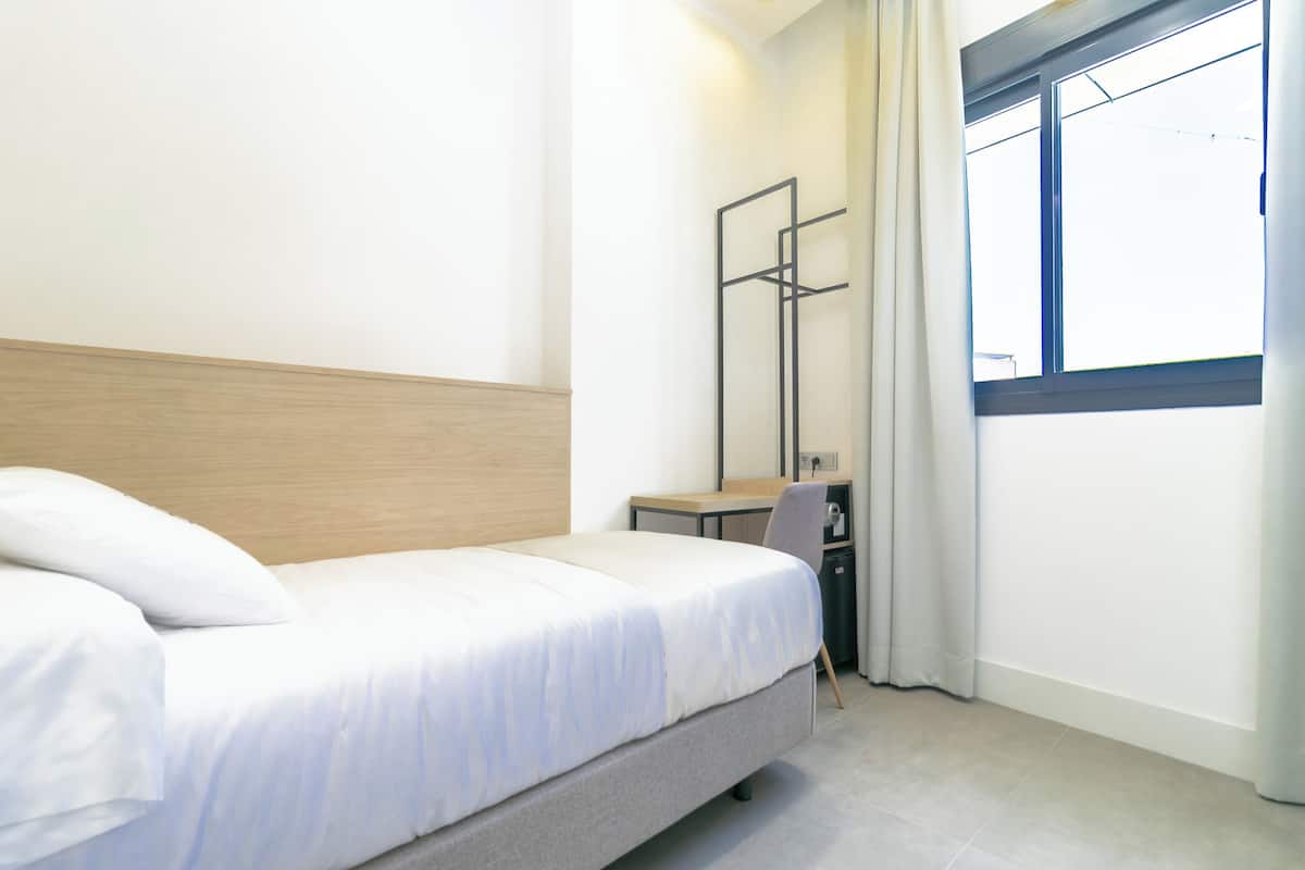 Quarto de hotel moderno com cama, escrivaninha e janela.