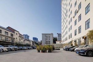 Um estacionamento com vários carros, um edifício de fachada plana e um céu claro.