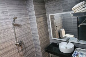 Uma casa de banho moderna com azulejos cinzentos, uma sanita preta, um espelho e um porta-toalhas.