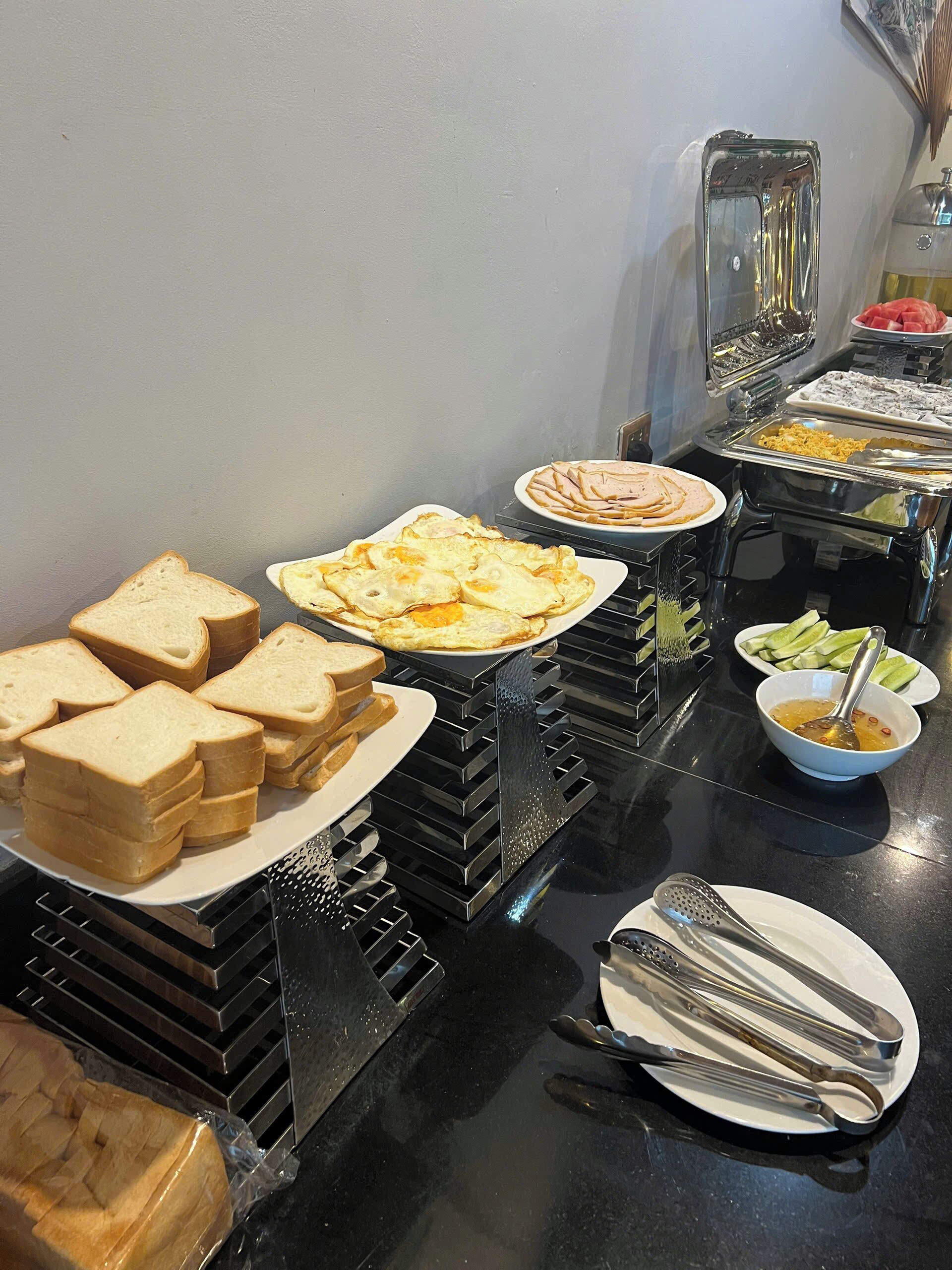 Buffet com diversos alimentos, incluindo pão, ovos e legumes.