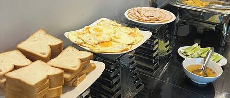 Buffet com diversos alimentos, incluindo pão, ovos e legumes.